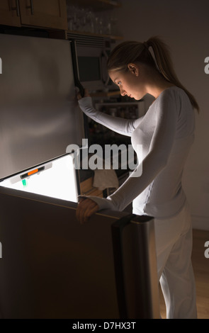 Woman opening fridge at night Stock Photo - Alamy