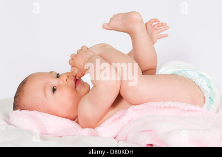 Playful baby girl trying to eat feet Stock Photo - Alamy