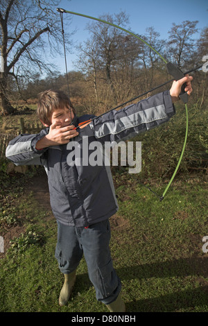 Boy firing an arrow from his bow holding his bow and pulling hard Stock ...