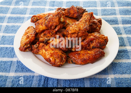 Spicy fried chicken wings in paprika sauce in a black plate on a dark ...