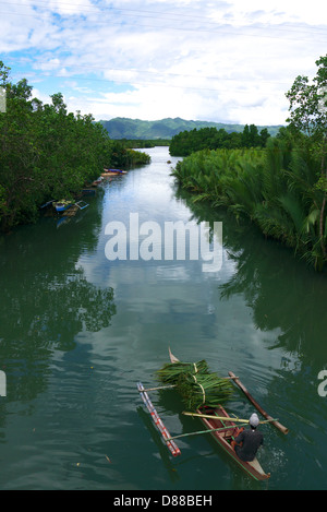 A traditional Filipino outrigger boat or bangka is anchored on a quiet ...