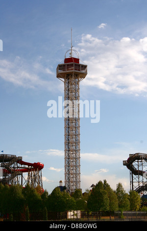 A tall observation tower stands in the shade of trees in an ...