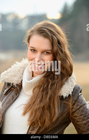 portrait of young smiling germany woman in dress near roses in a garden ...