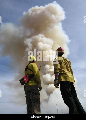 Firefighters in protective gear are positioned in front of and inside a ...
