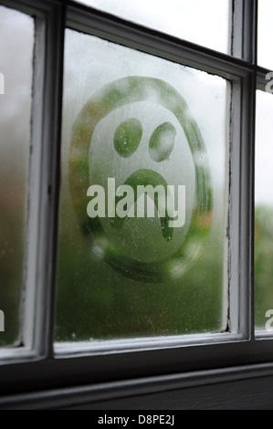 Sad face drawn on the condensation on a rainy window Stock Photo - Alamy