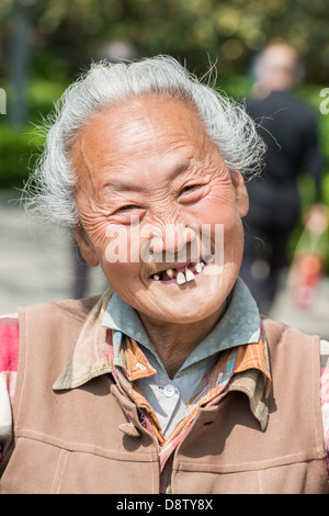 Funny asian senior woman in glittering disco dress and faux fur coat ...