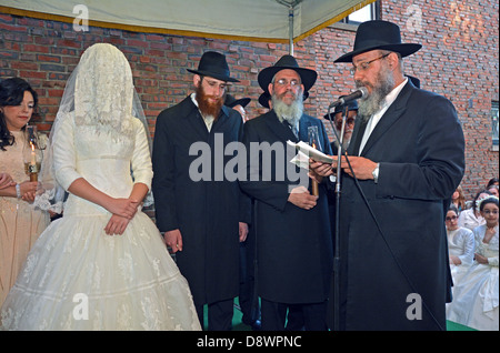 A orthodox religious Jewish bride and groom under a canopy at their ...