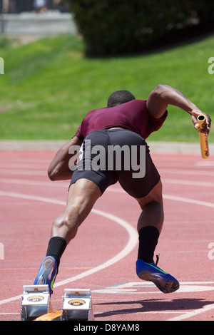 Runner in the starting blocks with baton Stock Photo - Alamy