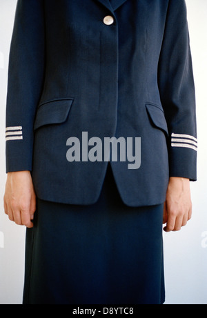 A flight attendant in a blue uniform stands on the runway next to an ...