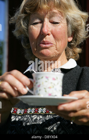 Happy senior woman drinking coffee and hands holding iron with basket ...