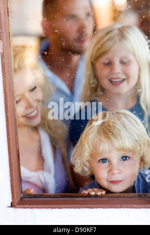 Family standing beside window, smiling Stock Photo - Alamy