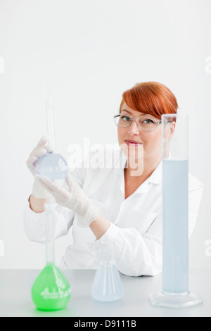 Smiling red-haired scientist looking at the camera while holding a test ...