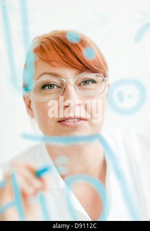 Smiling red-haired scientist looking at the camera while holding a test ...