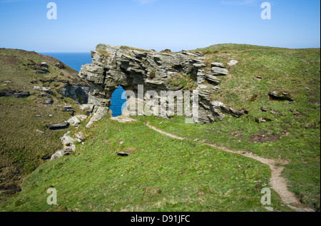 rugged coastline with rock arch in evening light Lands End Cornwall ...