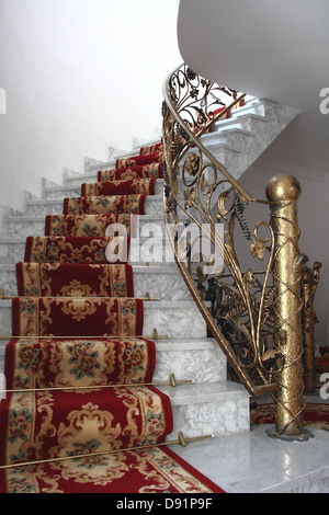 Detail of a golden metal marble staircase railing with a varnished ...