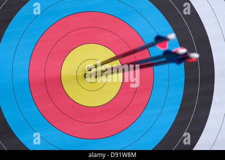 Three arrows embedded in the dead centre of an archery target Focus on ...