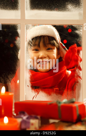 Girl looking at Christmas gift through window Stock Photo - Alamy