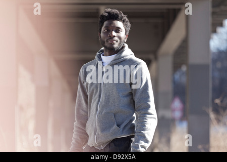 A hip young man standing under a city bridge in sports gear Stock Photo ...
