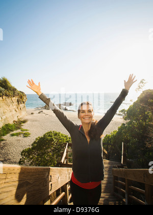 Mixed race woman climbing steps on beach Stock Photo - Alamy