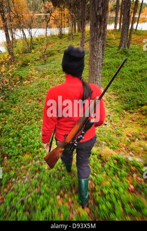 Hunter with rifle walking through the high grass by the forest Stock ...