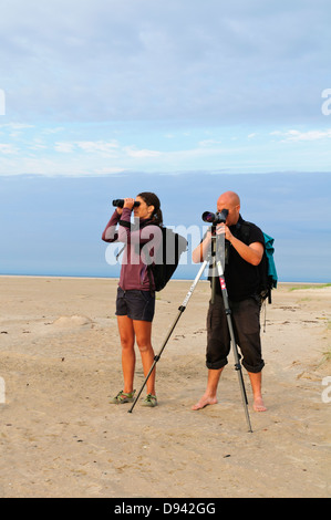 Two women watching birds with binoculars from a hide in WWT Slimbridge ...