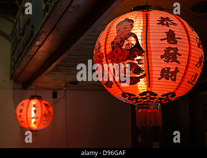 Red lanterns with Chinese writing hanging from wooden roof in autumn w ...
