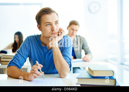 Portrait of handsome student carrying out test at lesson with ...