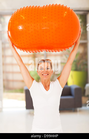 Middle aged woman holding orange fruit with happy face smiling doing ok ...