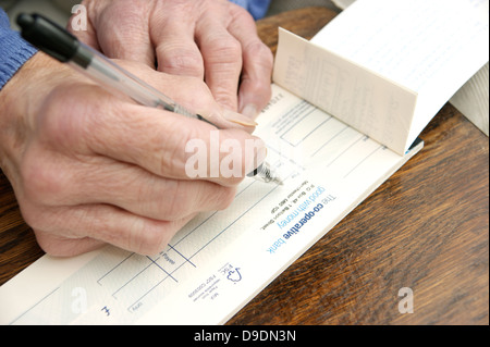 Elderly woman writing a cheque which is getting rarer these days (Co ...