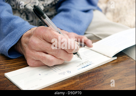 Elderly woman writing a cheque which is getting rarer these days (Co ...