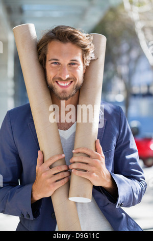 Portrait of an architect holding paper rolls and smiling Stock Photo ...