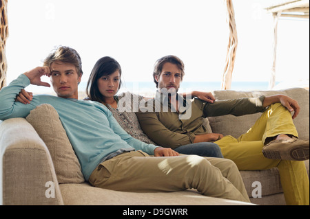 Three friends sitting together on a couch Stock Photo - Alamy