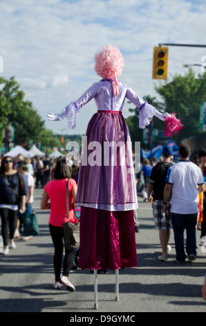 Female stilt walker in colorful costume with young woman spectator at ...
