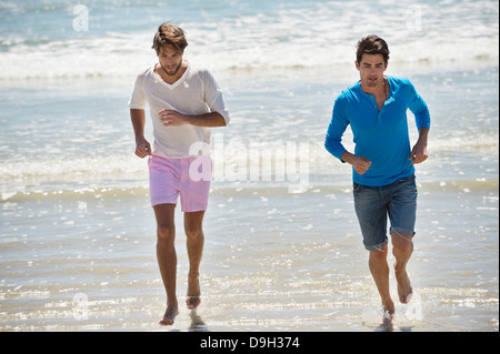 Two male friends running together on a trail through the forest Stock ...