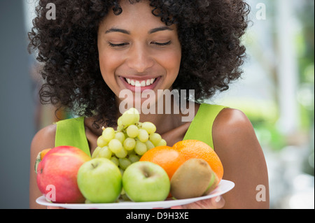 Smiling woman holding a plate of fruits Stock Photo - Alamy