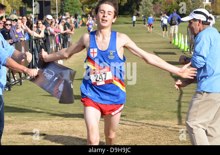 teenager crosses the finish line after running in a high school cross ...