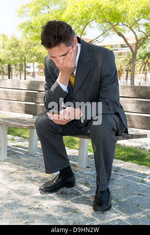 Worried businessman in a park bench with cellphone Stock Photo - Alamy