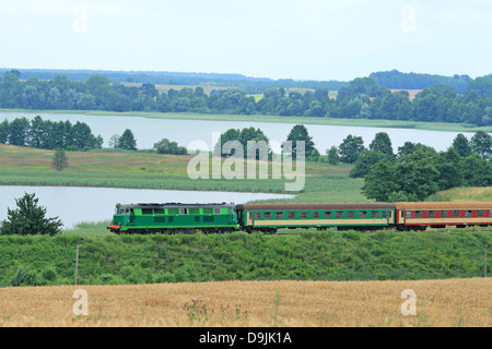 Passenger train passing through a green field, Germany Stock Photo - Alamy