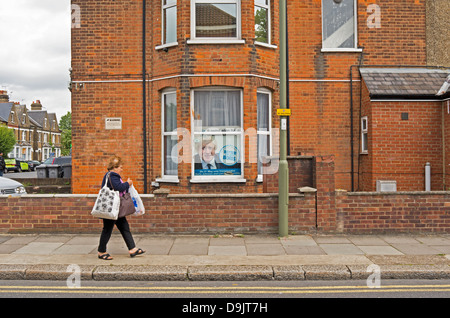 A woman walks past a campaign poster displayed outside the headquarters ...