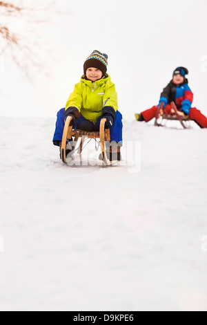 Two boys on toboggans in snow Stock Photo - Alamy