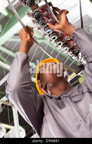 African American textile industrial mechanic repairing weaving loom ...