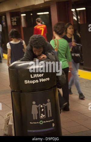 A homeless man looking through a garbage can bin in affluent area of ...