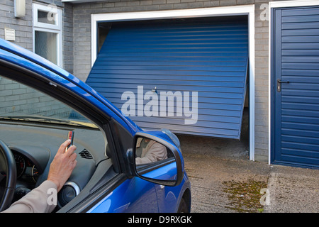 Woman car driver operating Henderson remote control to open or close ...
