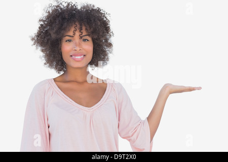 Pretty woman holding hand out in presentation and smiling at camera ...