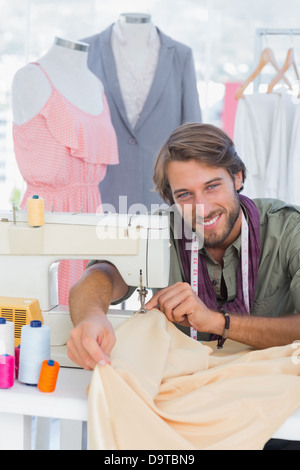 Smiling man fashion designer sewing with equipment Stock Photo - Alamy