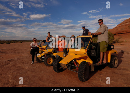 Tourists posing on tomcar a little Israeli buggy jeep at Arches ...