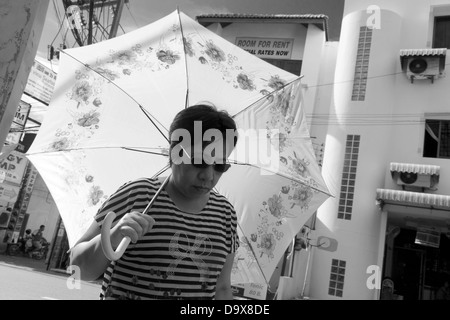 A woman shields herself from the sun with an umbrella as she walks near ...