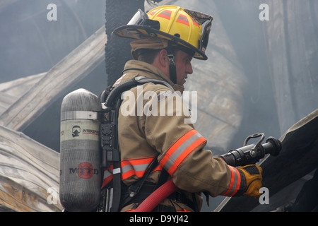 Male Firefighter holding fire hose in front of fire truck wearing Stock ...