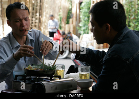 Men eating at a traditional Vietnamese street food pop-up cafe in Hanoi ...