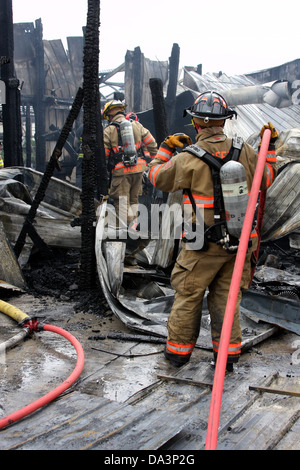A firefighter pulling a hoseline at an emergency fire scene Stock Photo ...